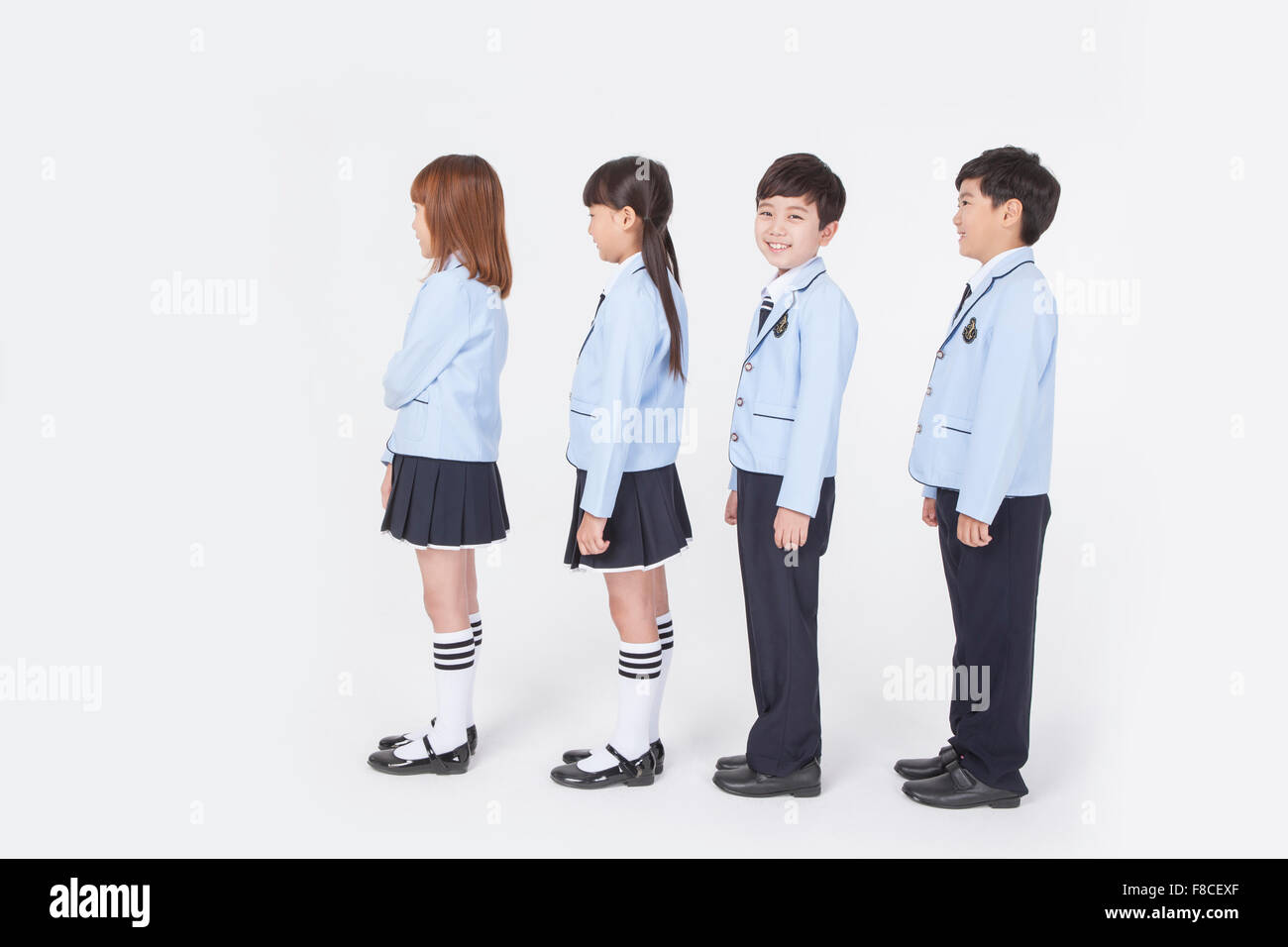 Four elementary school students in school uniforms standing in line and ...