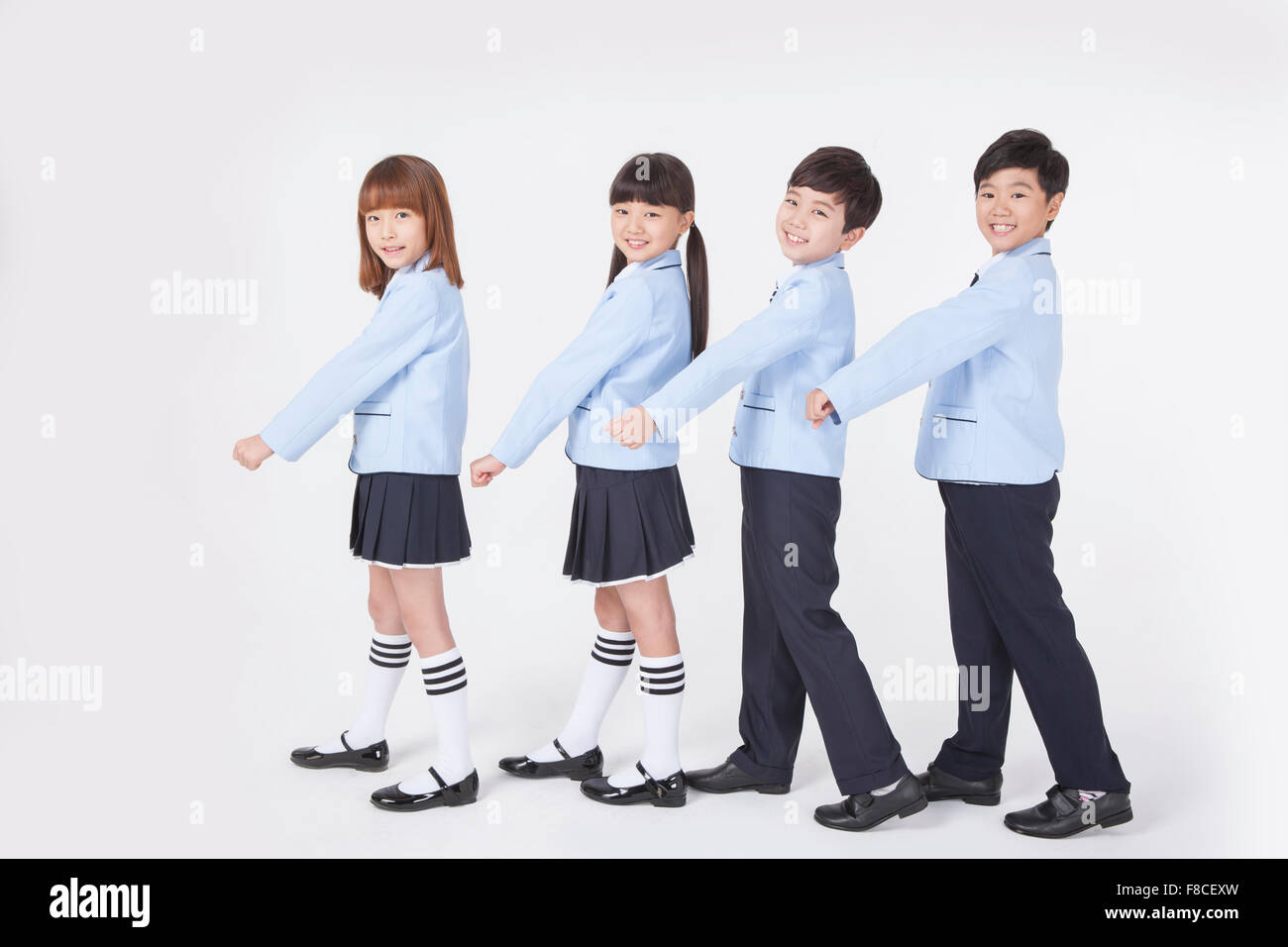 Four elementary school students in school uniforms standing in line and ...