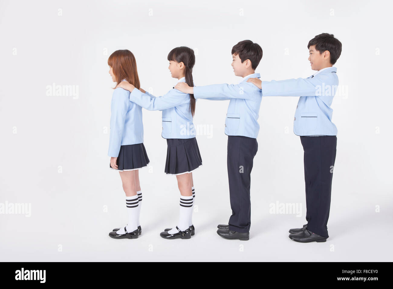 Four elementary school students in school uniforms standing in line ...