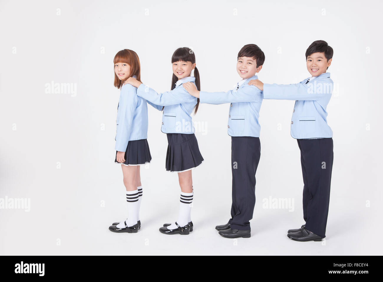 Four elementary school students in school uniforms standing in line ...