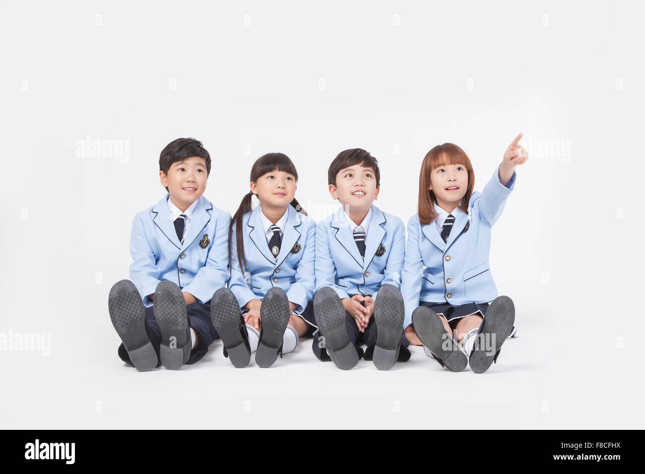 Four elementary school students sitting down and a girl among them ...