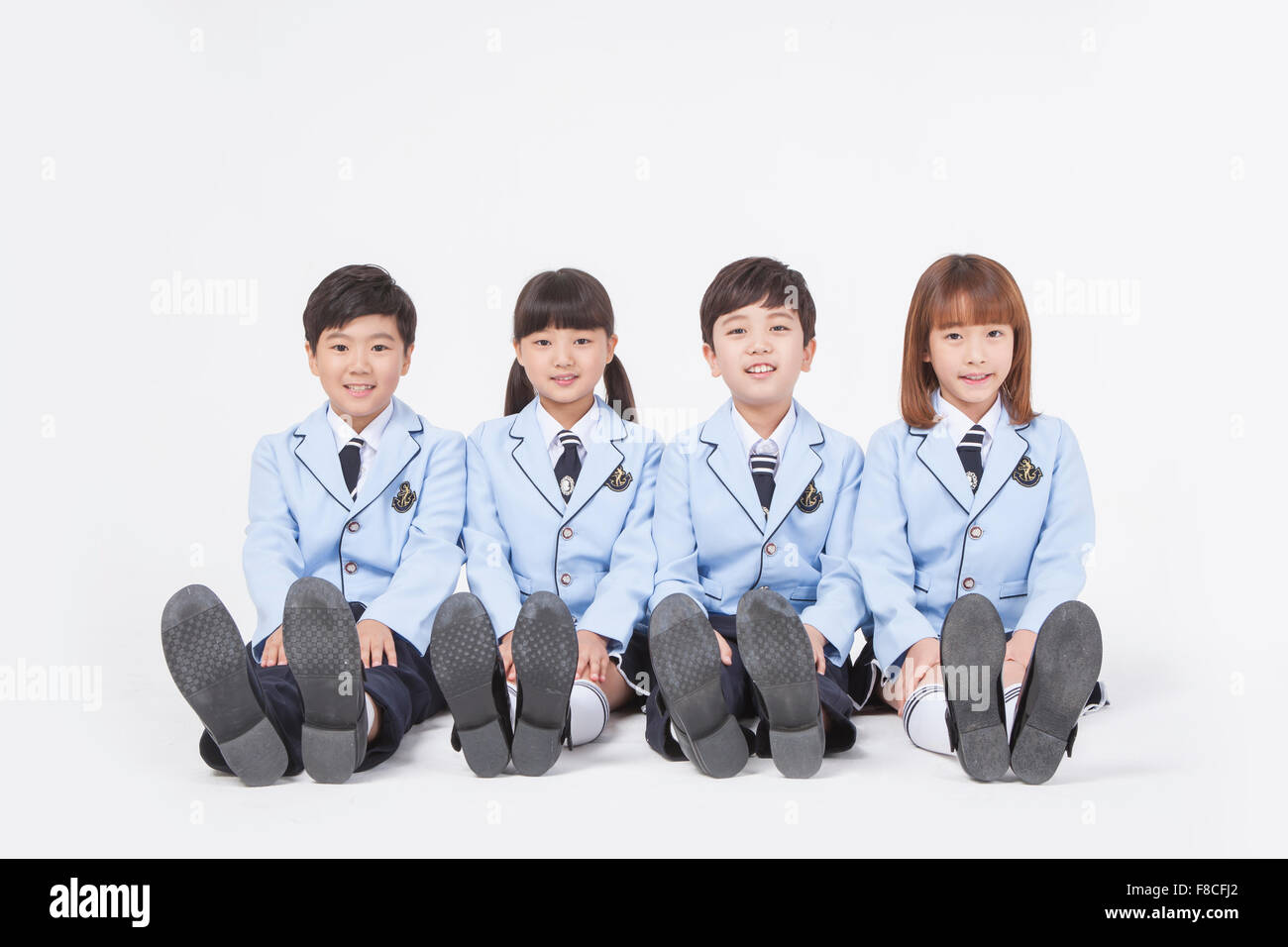 Four elementary school students in school uniforms sitting down ...