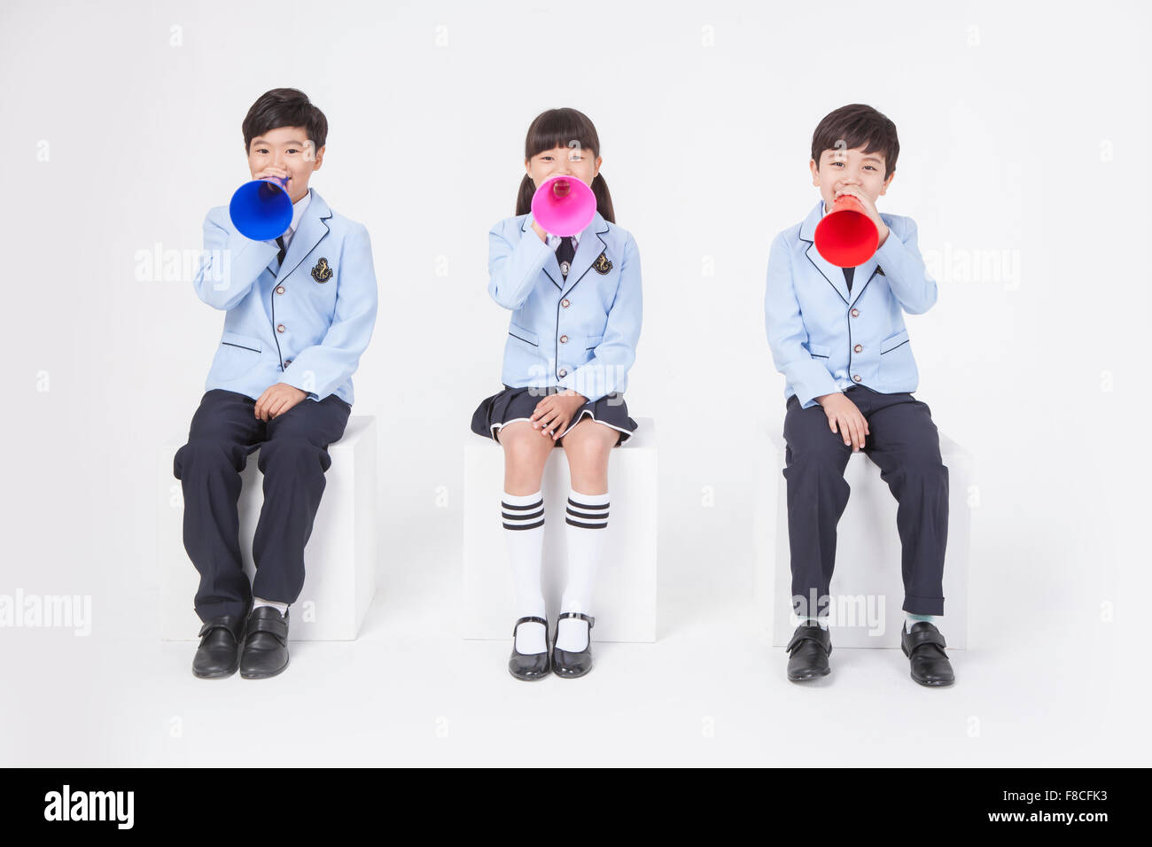 Three elementary school students in school uniforms sitting and ...