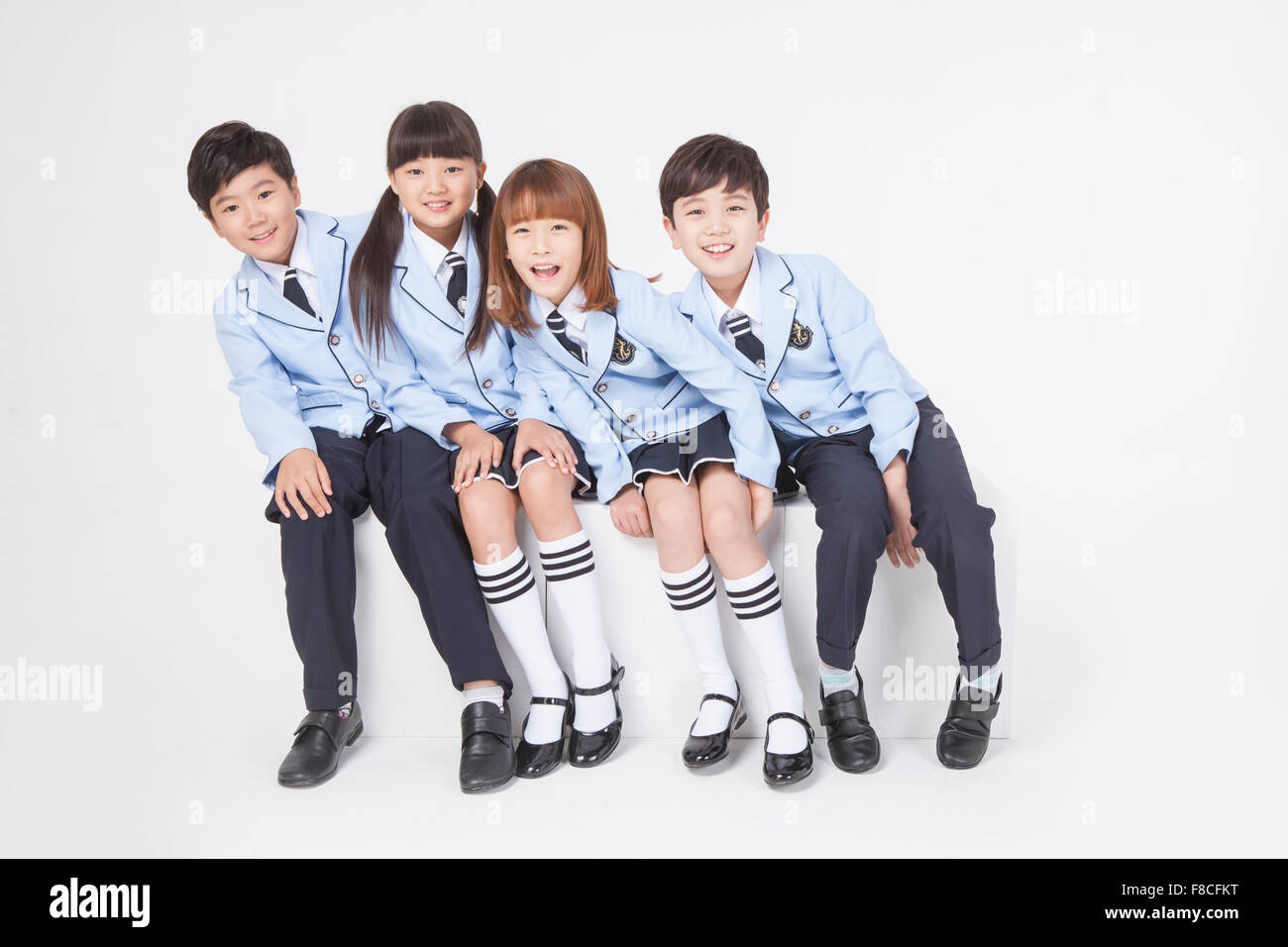 Four elementary school students in school uniforms sitting together and ...