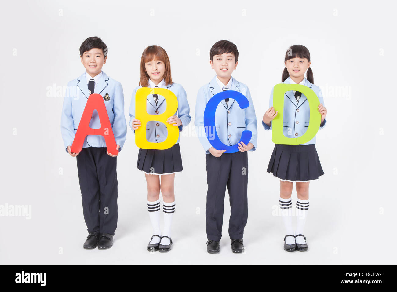 Four elementary school students in school uniforms standing and holding ...