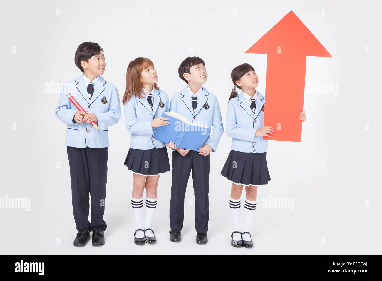 Four elementary school students standing with a big red pencil, a book ...