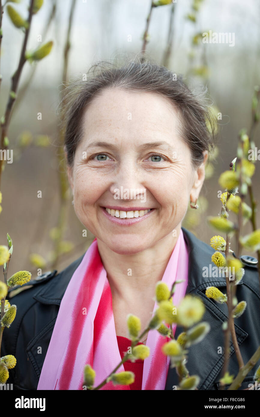 portrait of happy mature woman against spring willow branches with buds ...