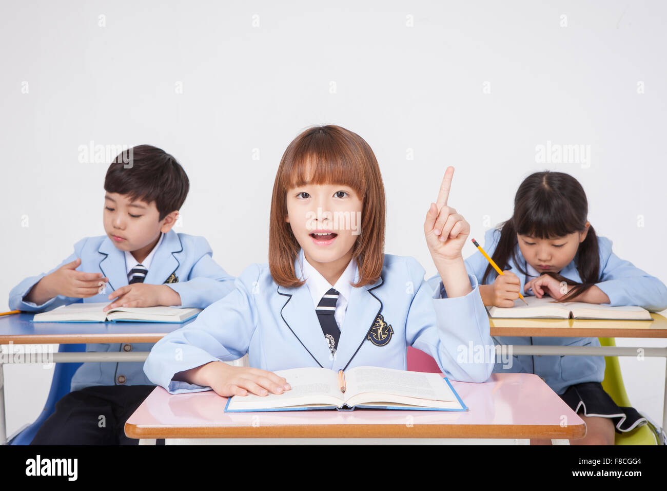 Elementary school girl in school uniforms seated at desk staring ...