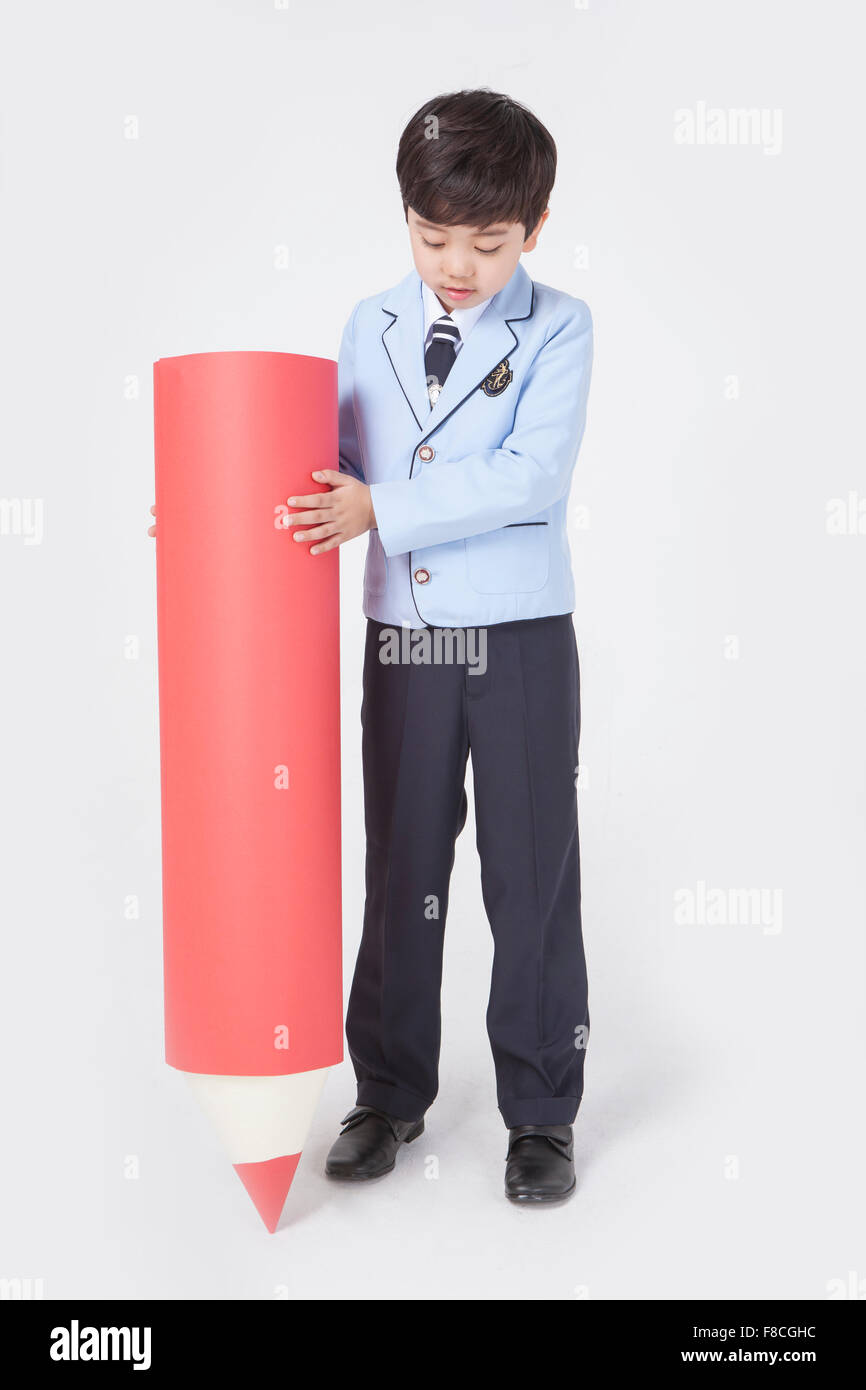 Elementary school boy in school uniforms standing with a big red pencil ...