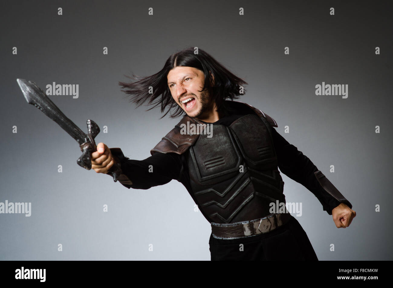 Angry knight with sword against dark background Stock Photo - Alamy