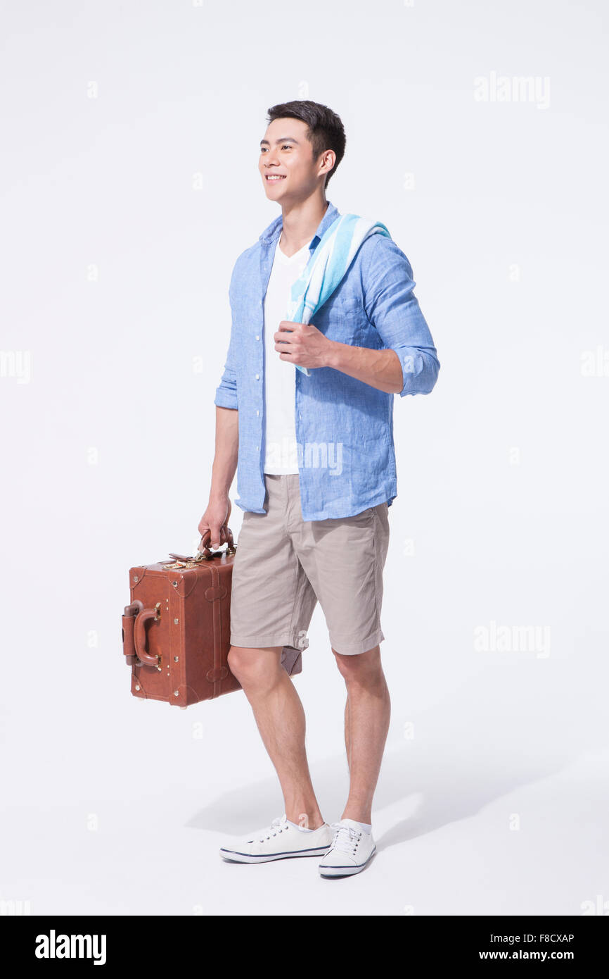 Man in casual outfits standing and holding a suitcase in one hand and a ...