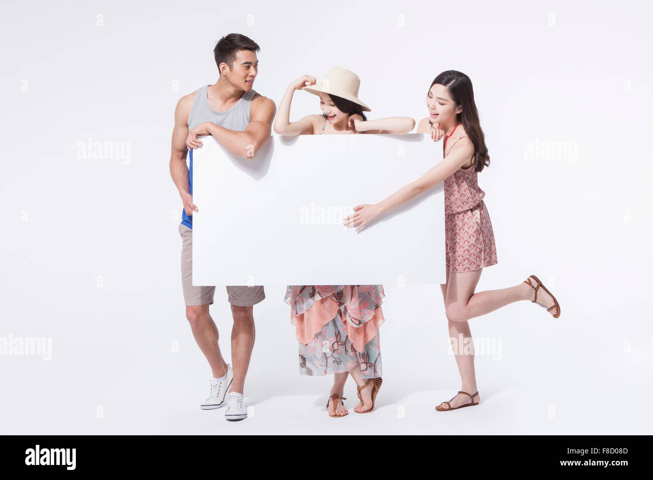 Two women and a man in tourist style of fashion standing and holding a ...
