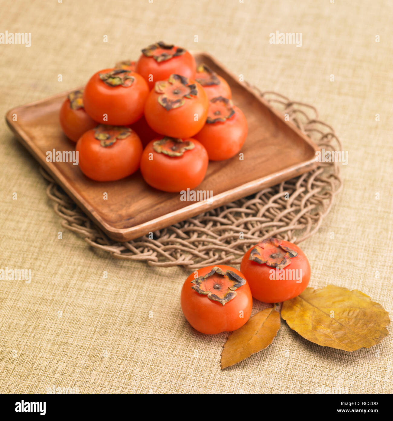 Ripe persimmons on wood tray and two other persimmons with the ...