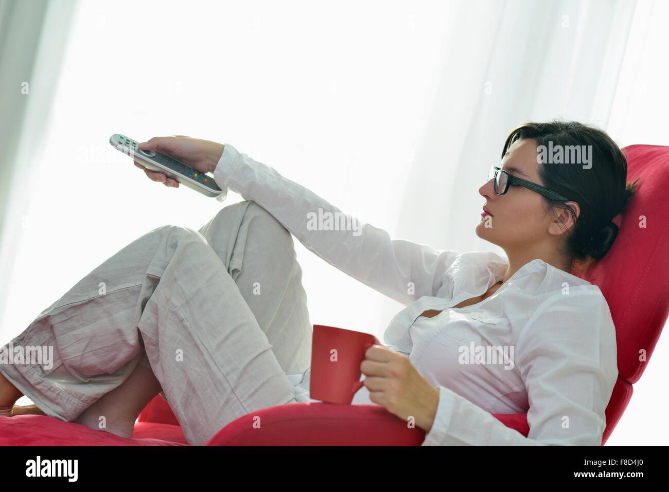 happy young woman watching tv at modern home livingroom Stock Photo - Alamy