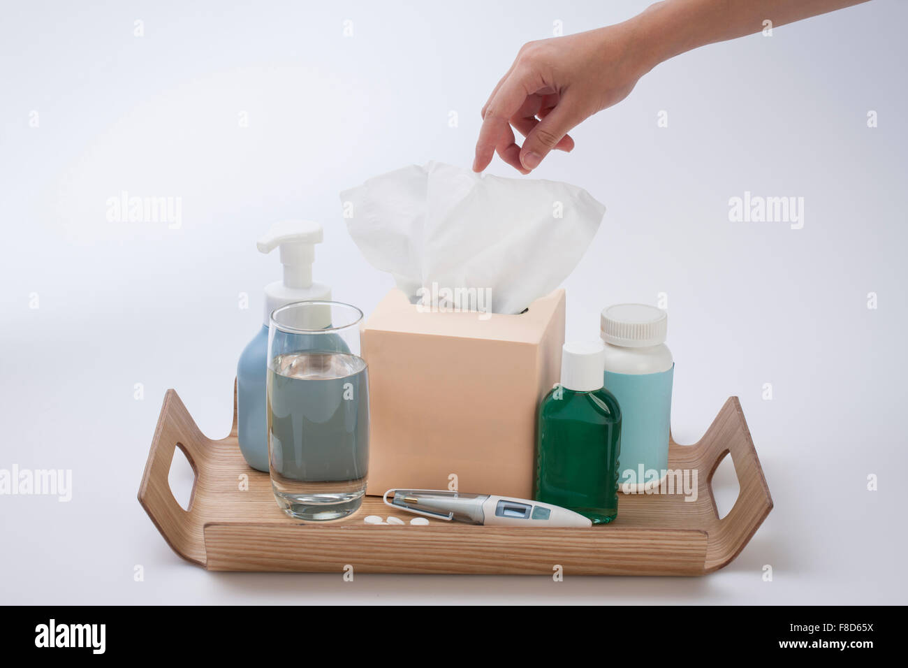 Tissue in a box touched by a hand and other objects on a tray related ...