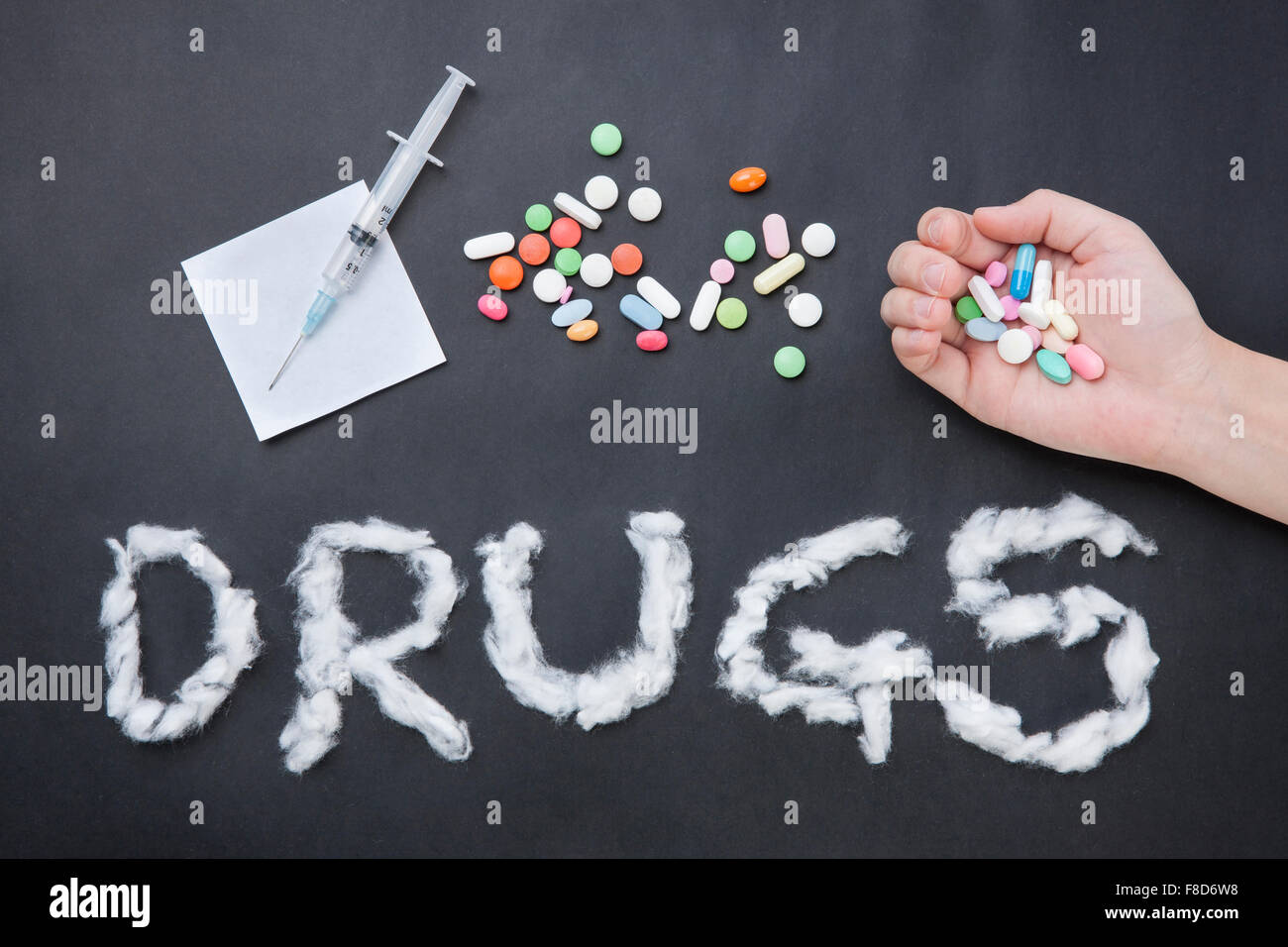 Word DRUGS written with cottons on black background with pills and ...