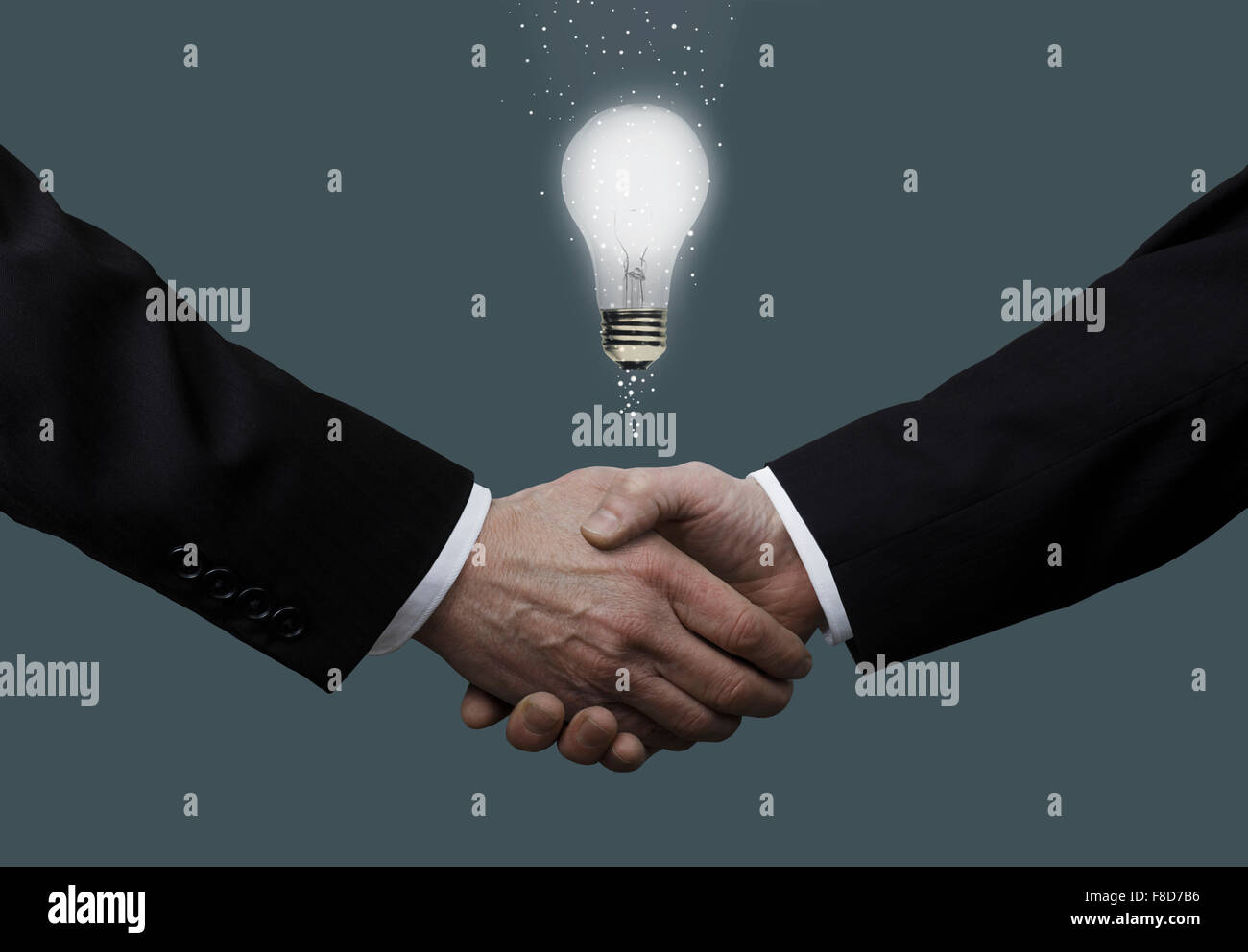 Studio shot of a businessmen shaking hands with a light bulb floating ...