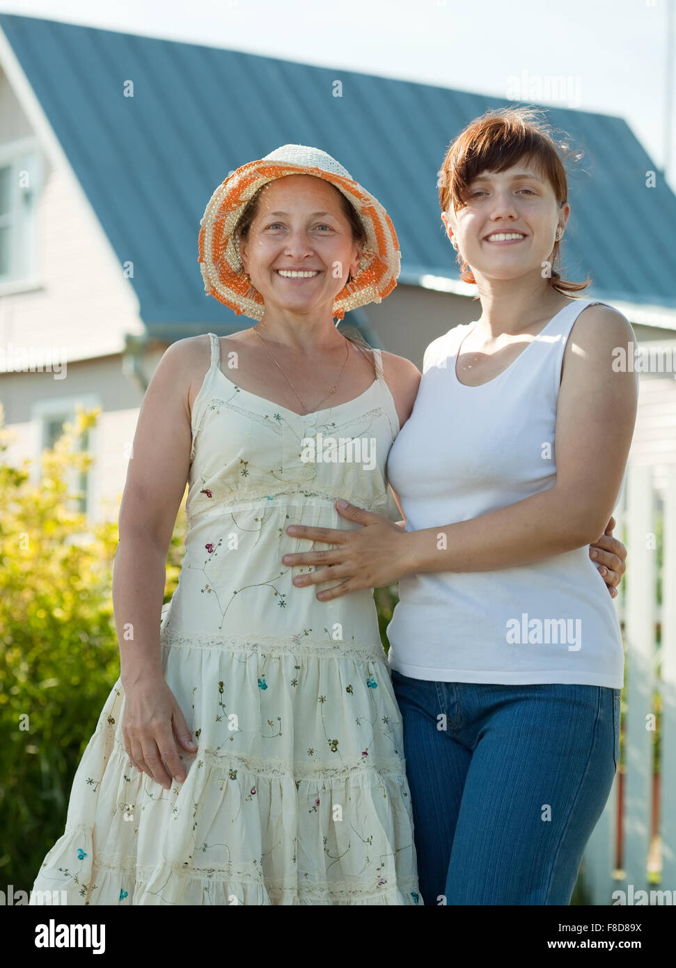 Two happy women posing in front of her residence Stock Photo - Alamy