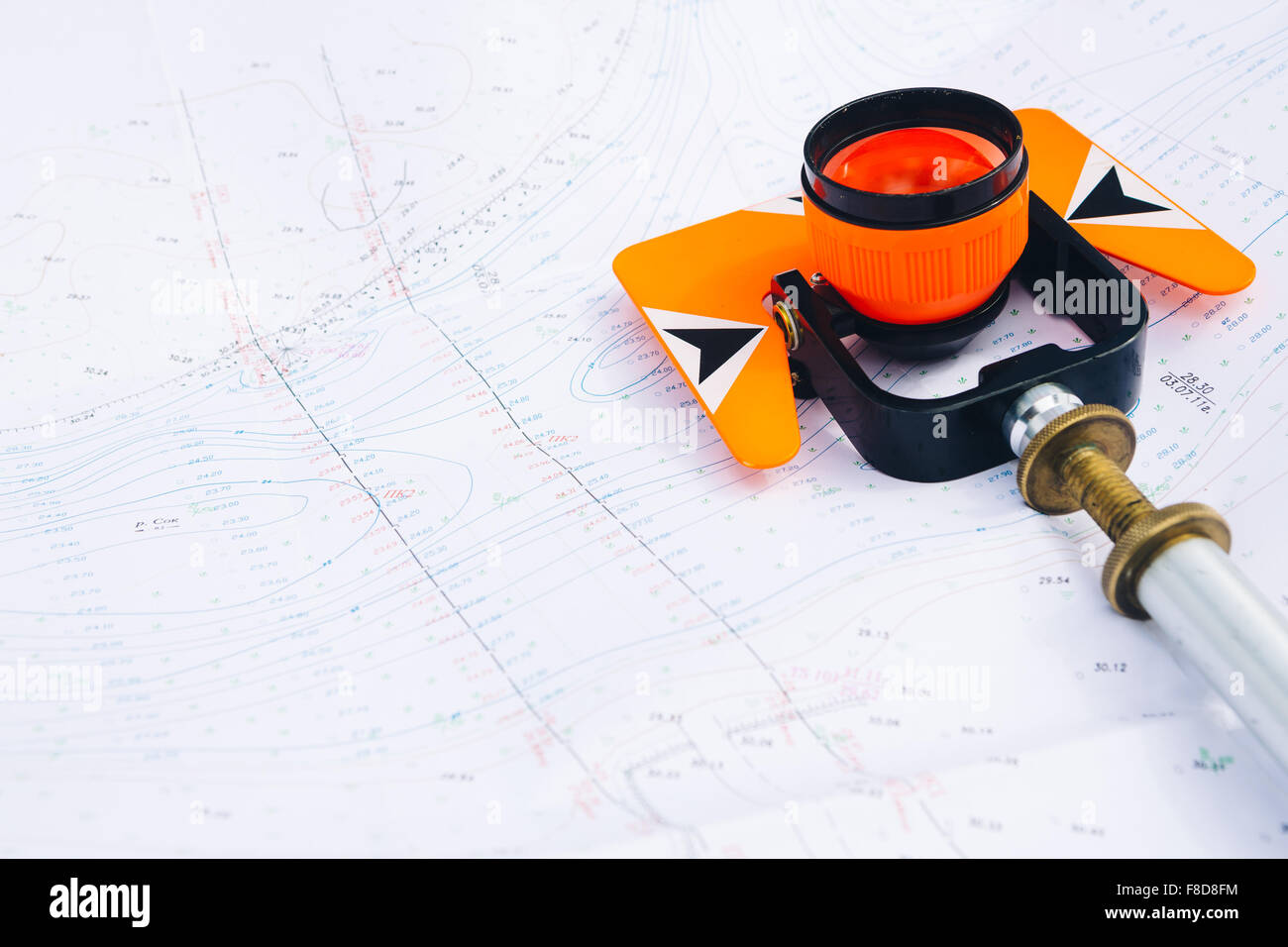 orange theodolite prism lies on a background of geodetic maps of the ...
