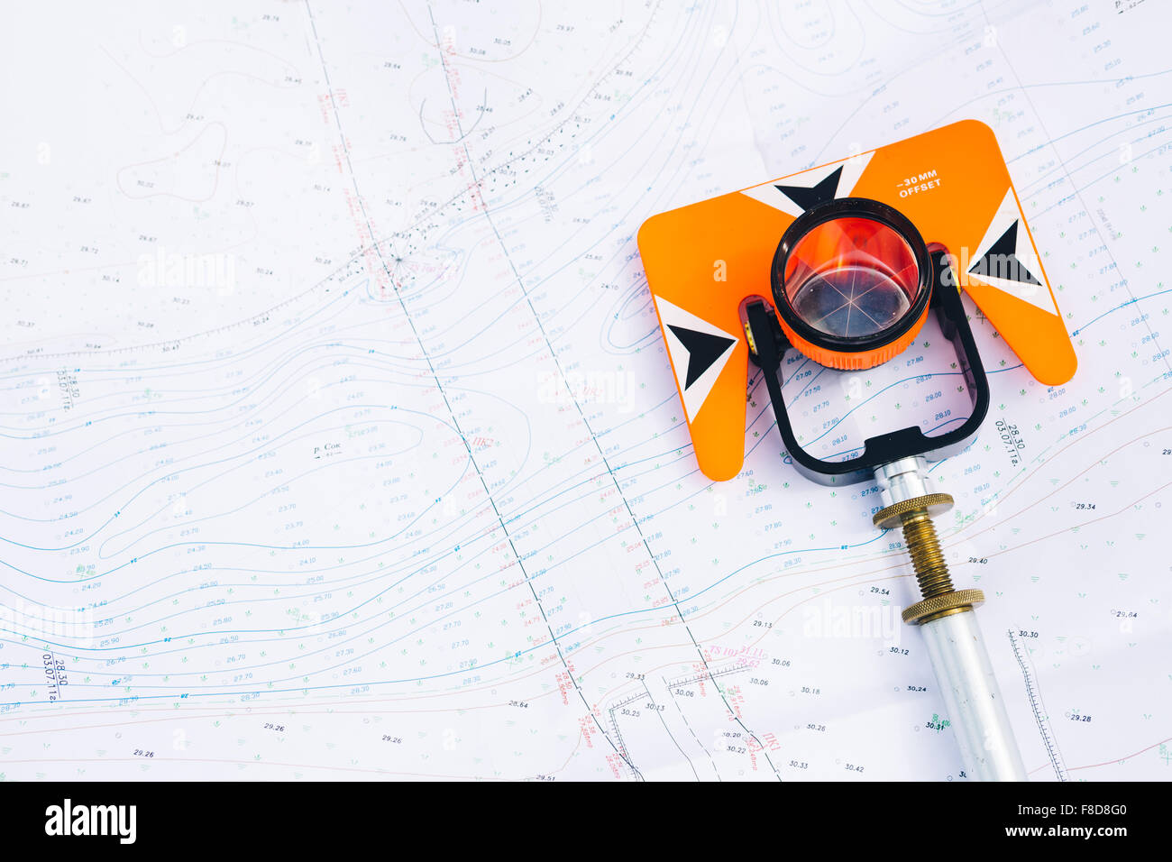 orange theodolite prism lies on a background of geodetic maps of the ...