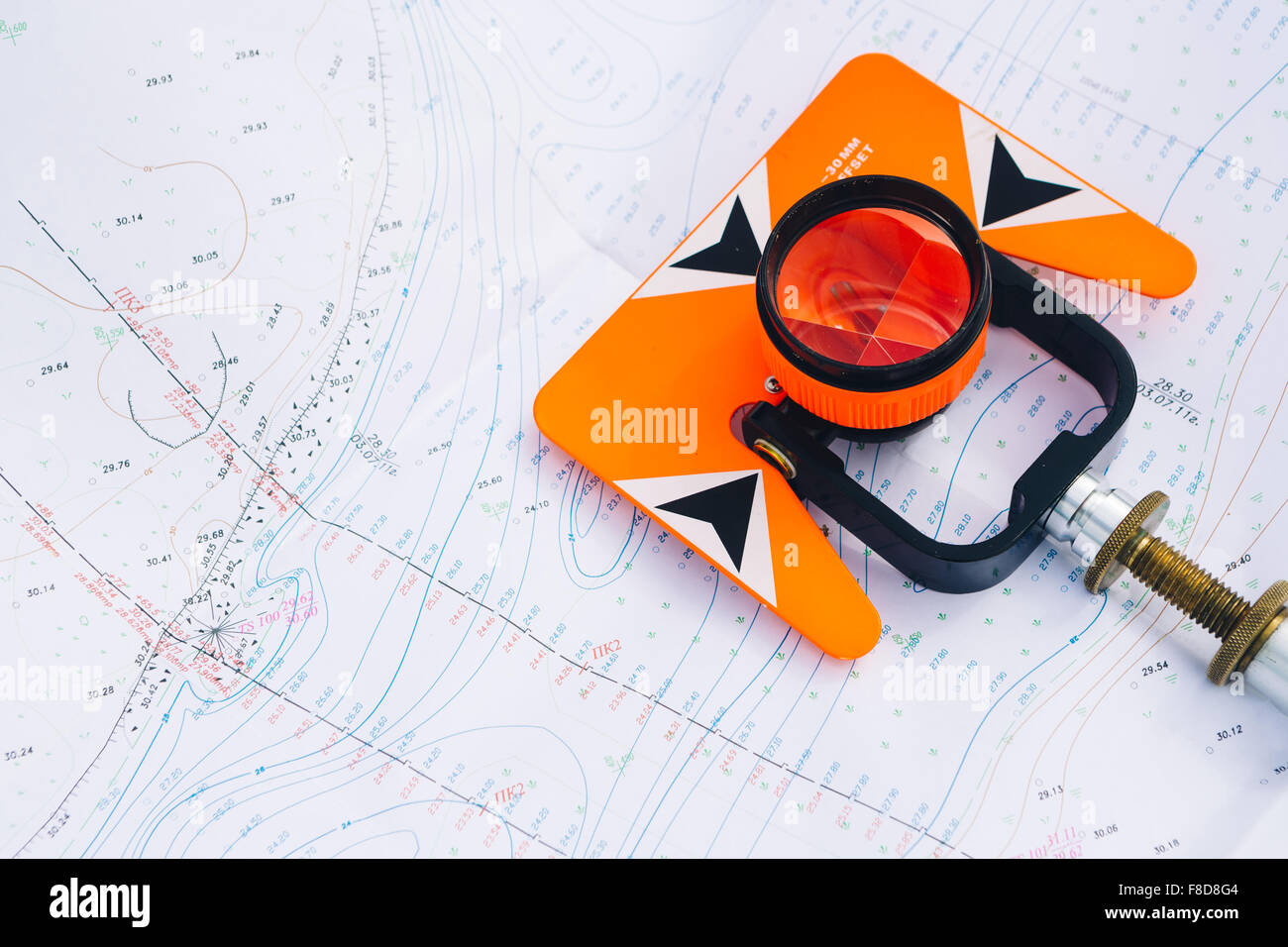orange theodolite prism lies on a background of geodetic maps of the ...