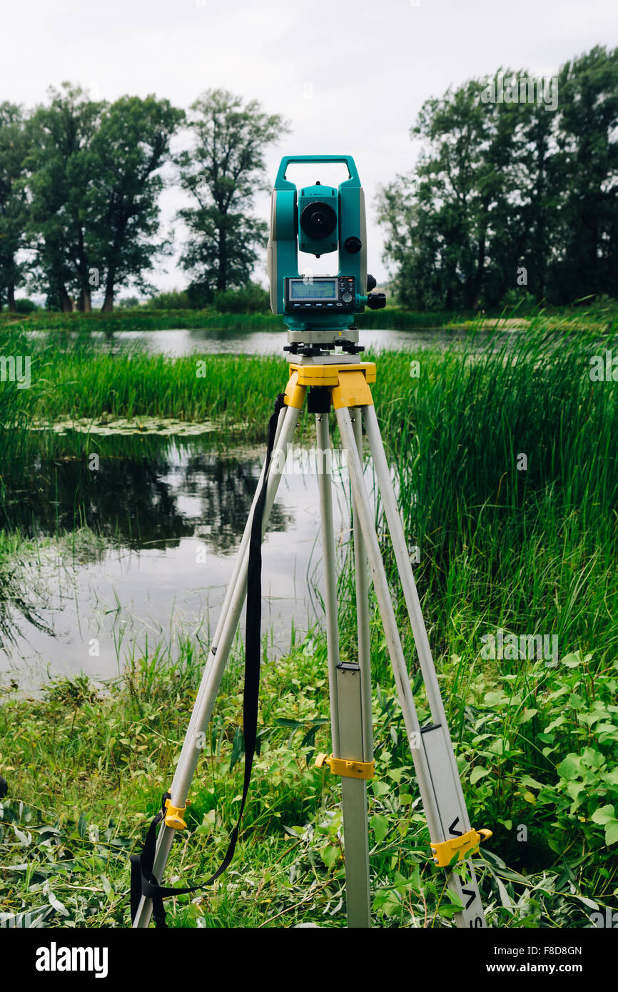 blue surveying equipment total station on a background of lake and ...