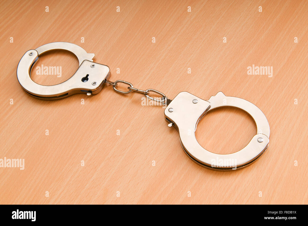 Metal handcuffs on the wooden background Stock Photo - Alamy