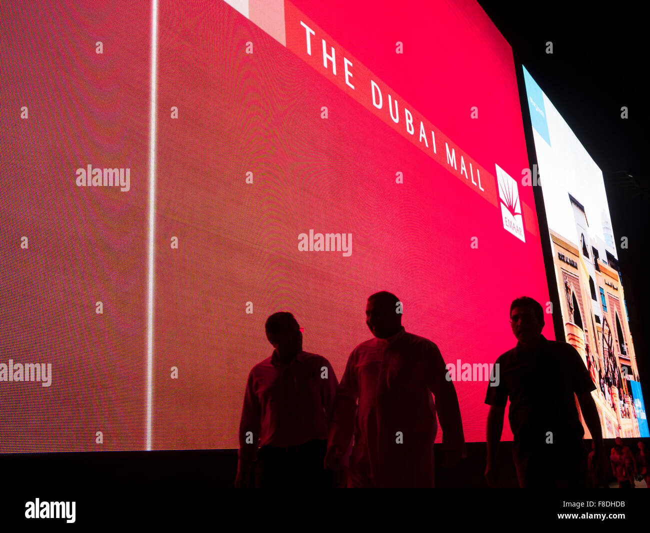 Silhouette of people in front of giant digital display of commercial ...