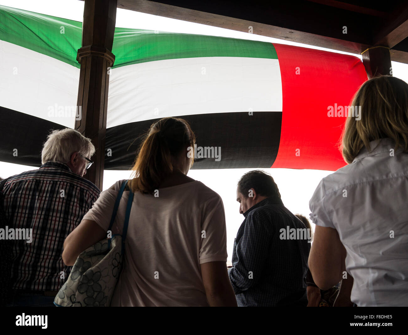 Tourists waiting for tour bus pickup under United Arab Emirates flag in ...