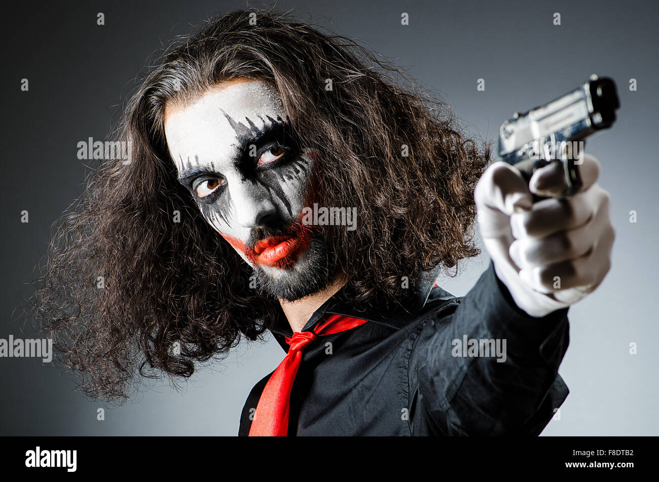 Evil clown with gun in dark room Stock Photo - Alamy