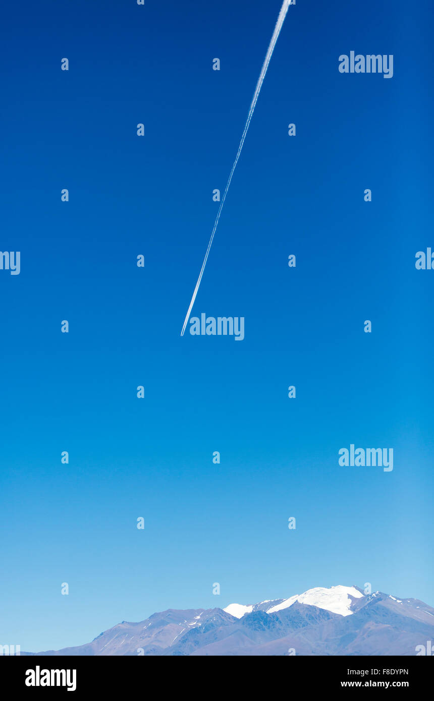 Closeup on airplane contrail against clear blue sky with the Aconcagua ...