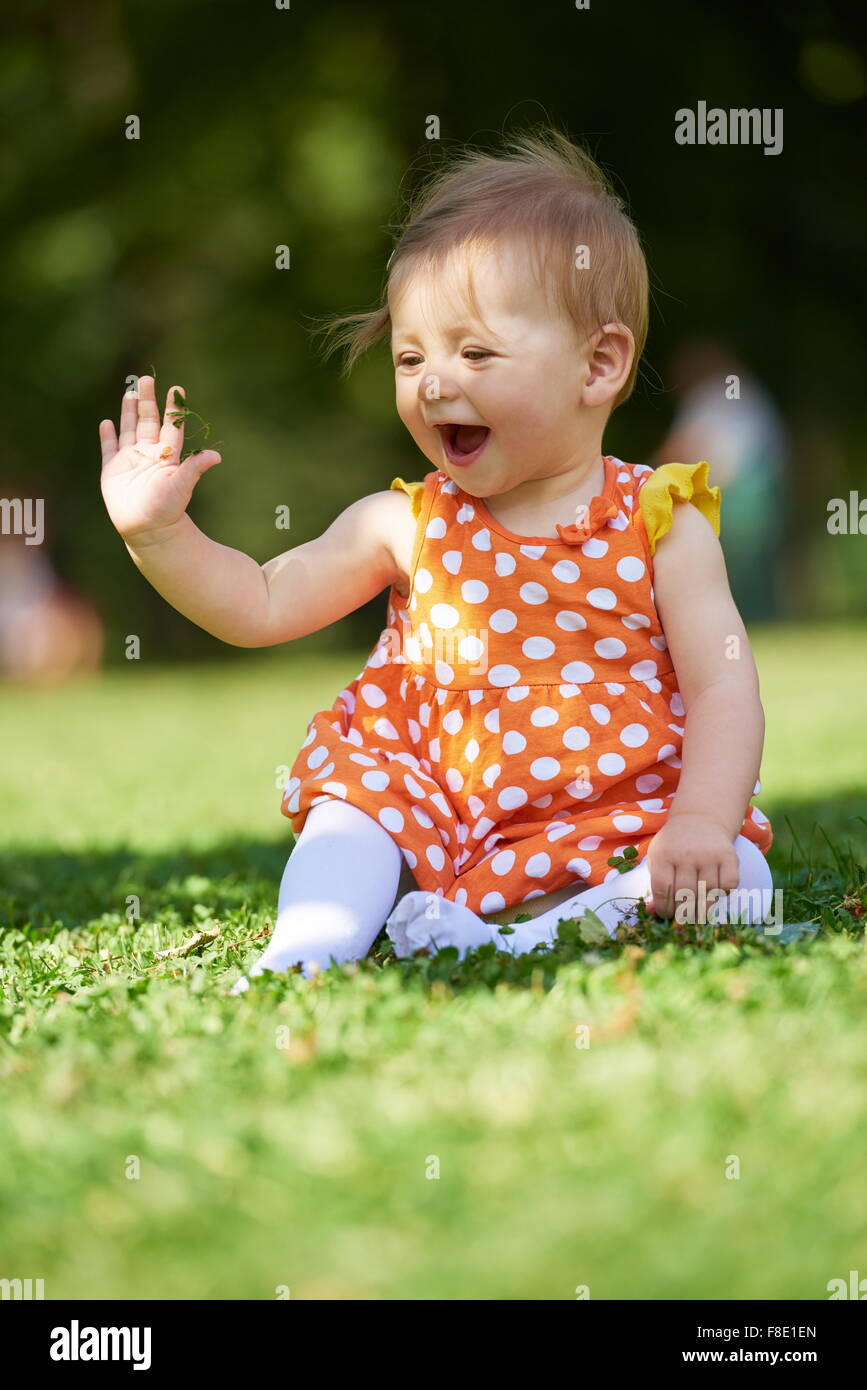 happy young baby child sittng on grass on beautiful summer day in park ...