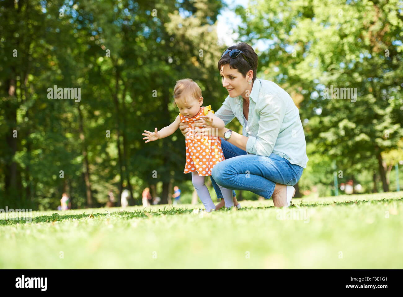 happy mother and baby child in park making first steps . Walking and ...