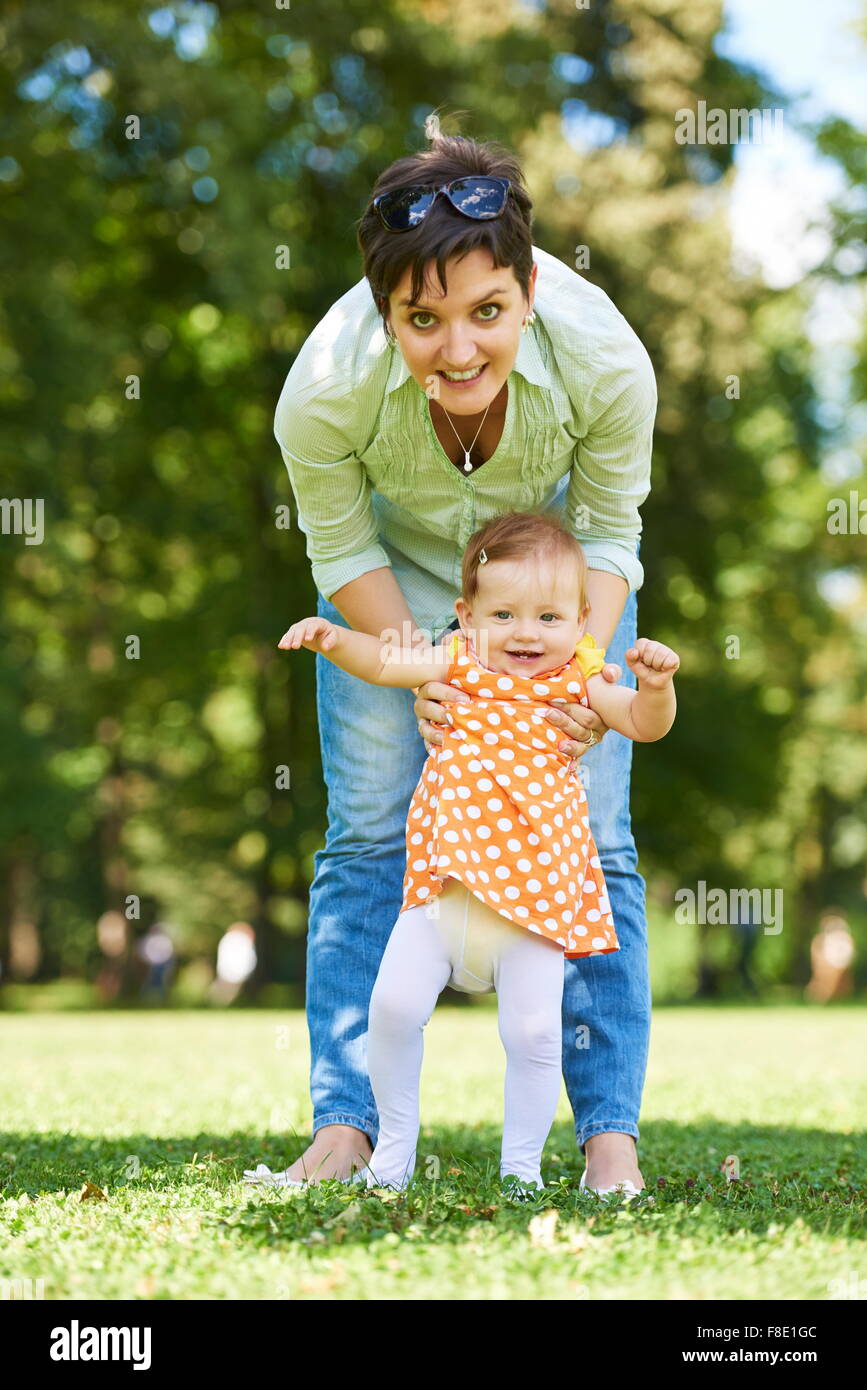 happy mother and baby child in park making first steps . Walking and ...
