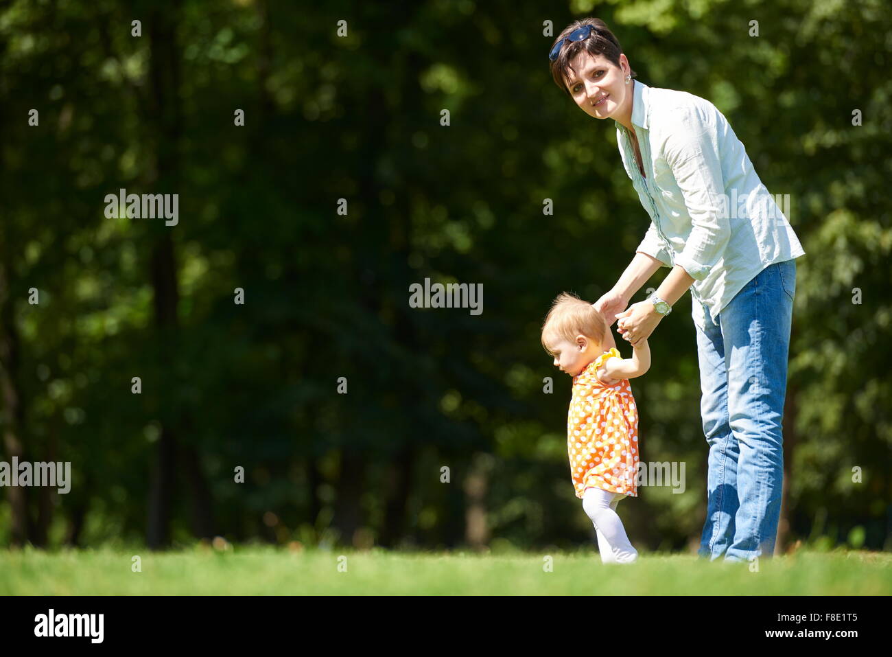 happy mother and baby child in park making first steps . Walking and ...