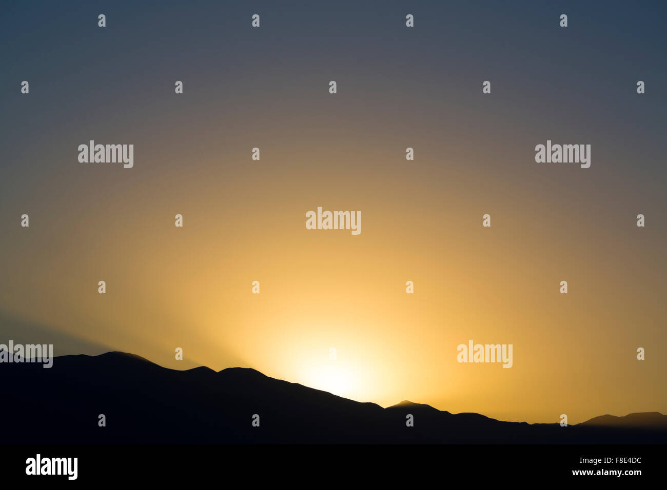 Dramatic sunset rays behind silhouette of mountain Stock Photo - Alamy