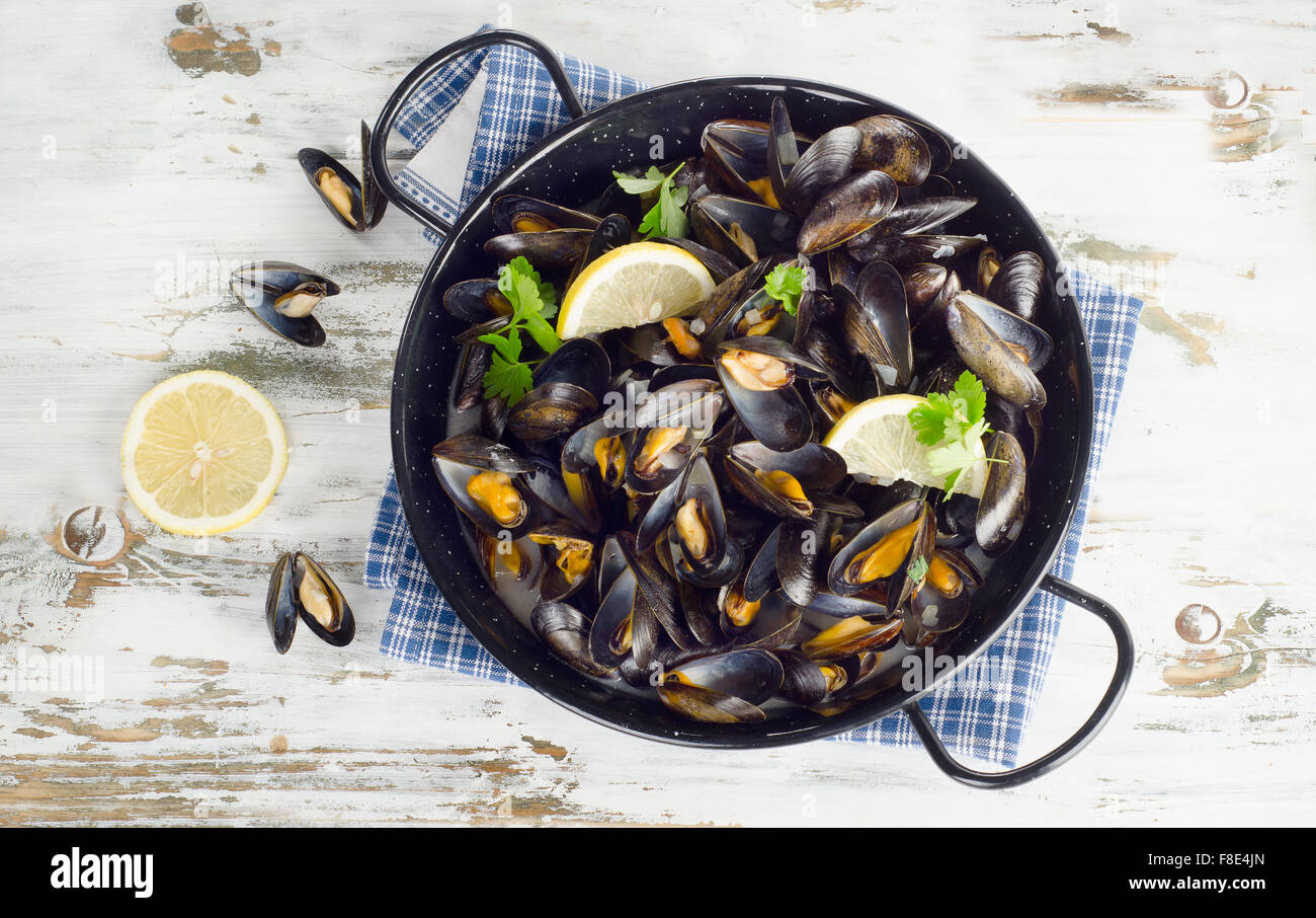 Copper pot of gourmet mussels served on a napkin garnished with lemon ...