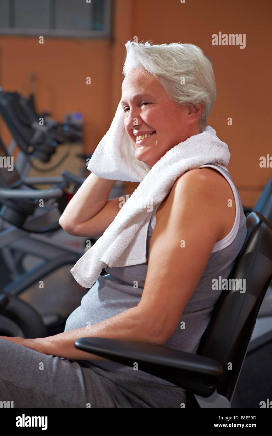 Senior woman sweating in gym and drying herself with towel Stock Photo ...