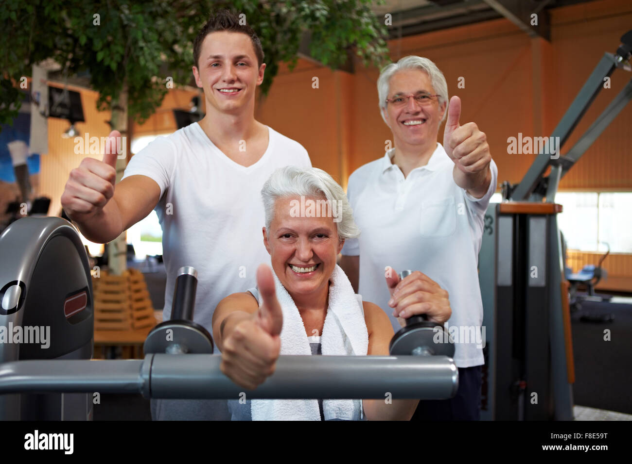 Successful fitness team in a gym holding thumbs up Stock Photo - Alamy