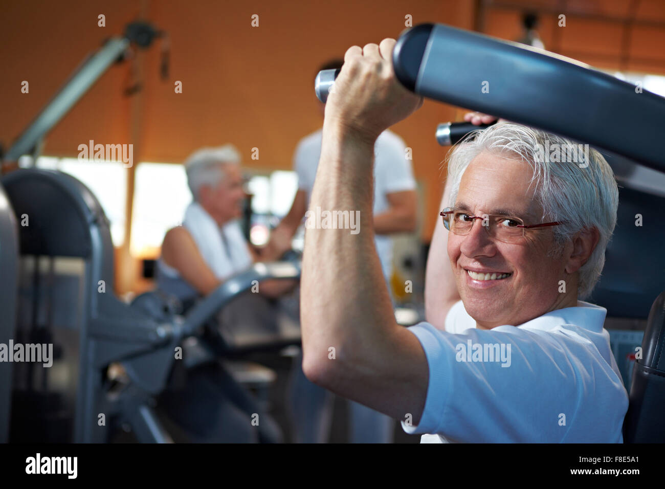 Two senior people working out in a gym with fitness coach Stock Photo ...