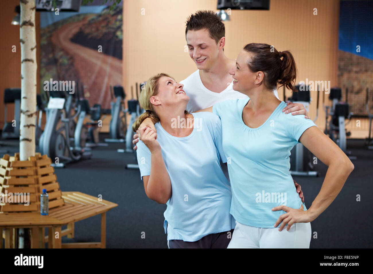 Two women and a man talking in gym Stock Photo - Alamy