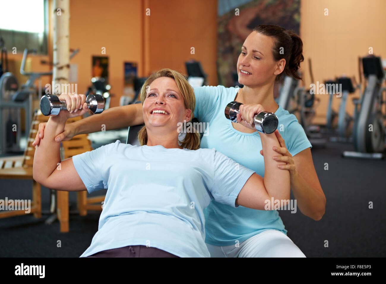 Woman doing weight training with female fitness coach Stock Photo - Alamy