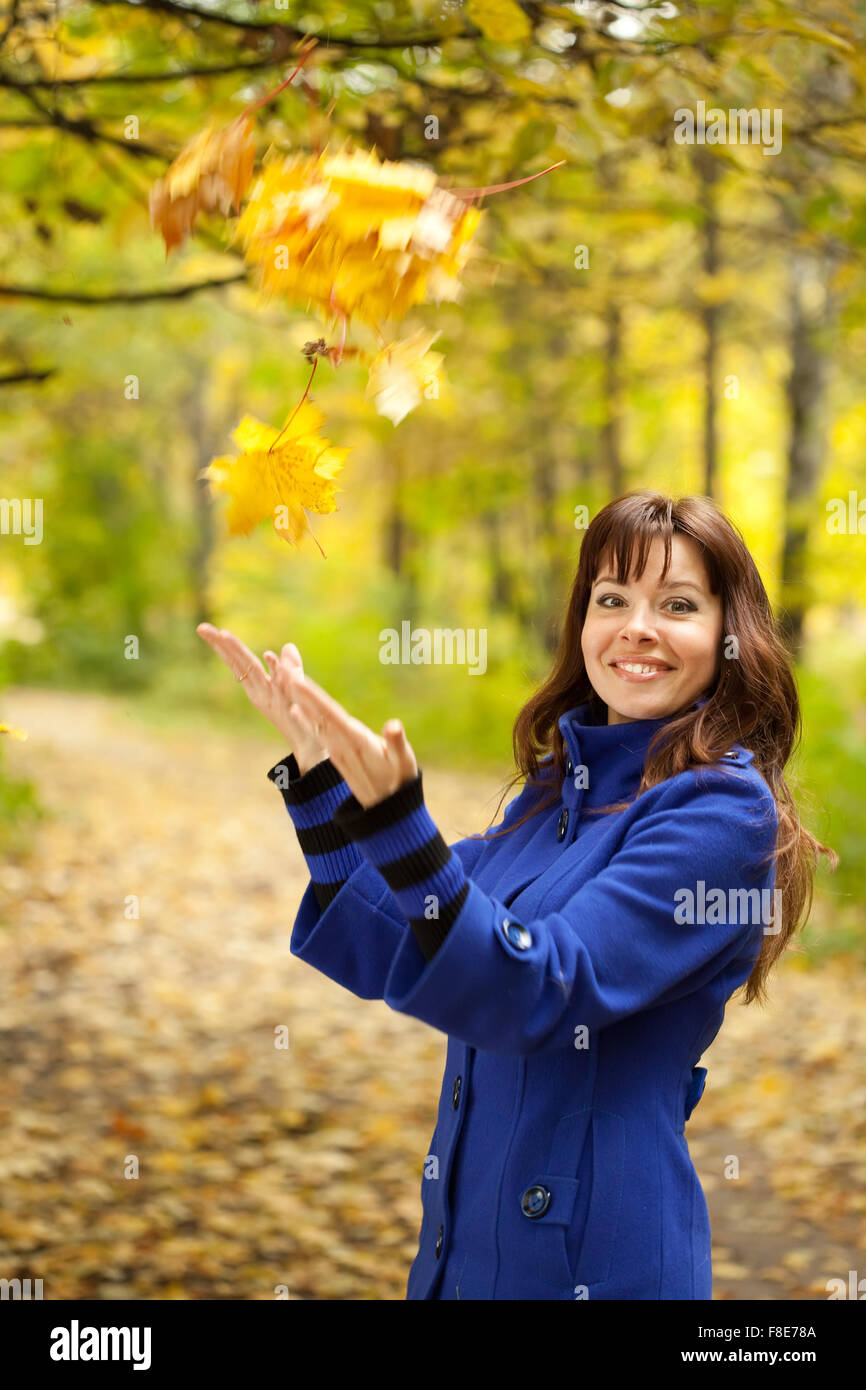 Girl in blue coat throwing leaves in the air Stock Photo - Alamy