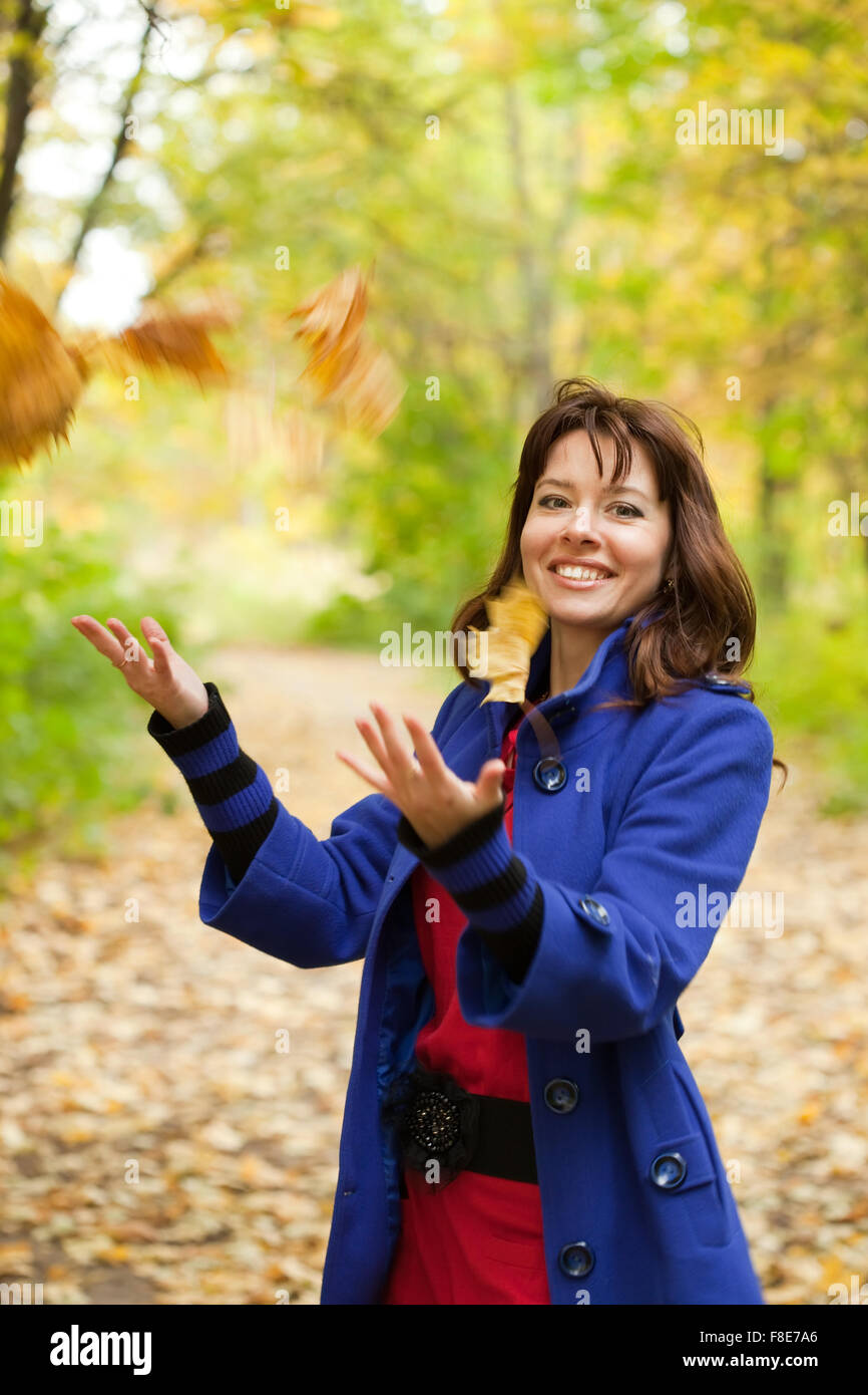 Girl in blue coat throwing leaves in the air Stock Photo - Alamy