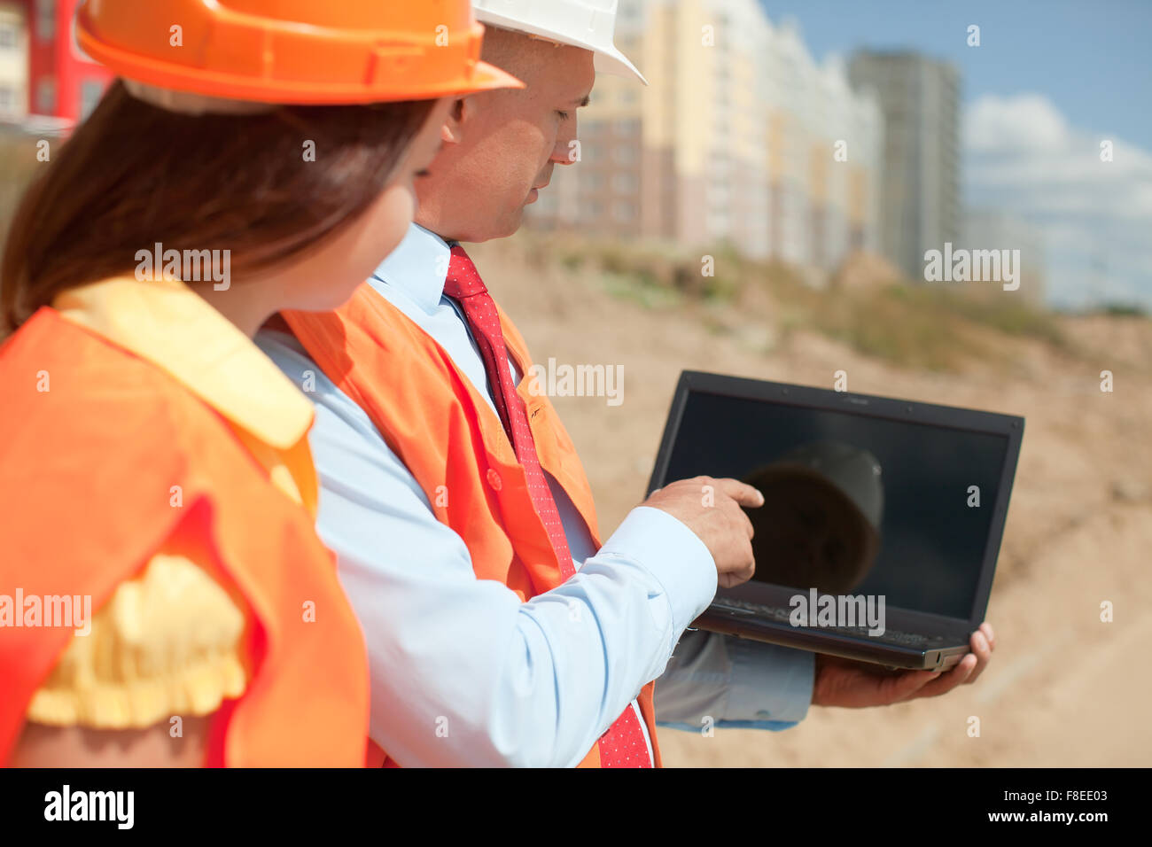 Two architects wearing protective helmet works in front of building ...