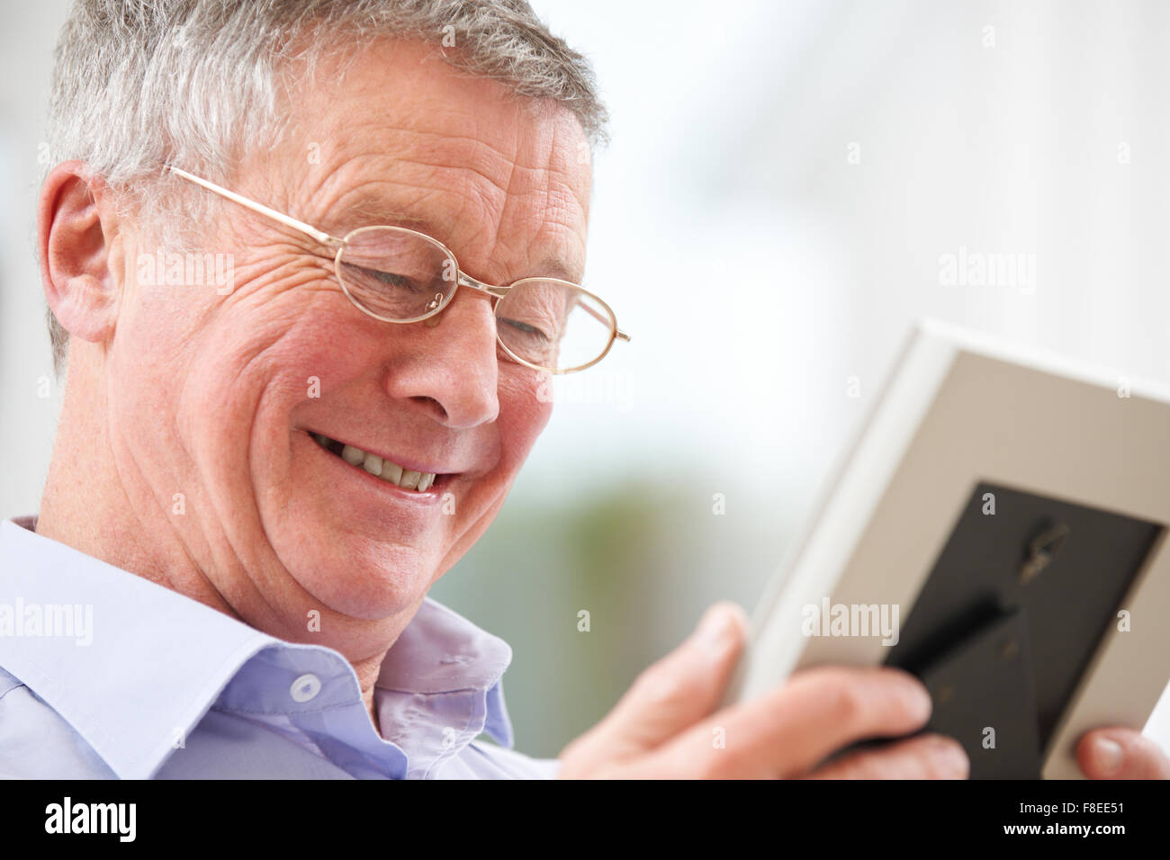 Smiling Senior Man Looking At Photograph In Frame Stock Photo - Alamy