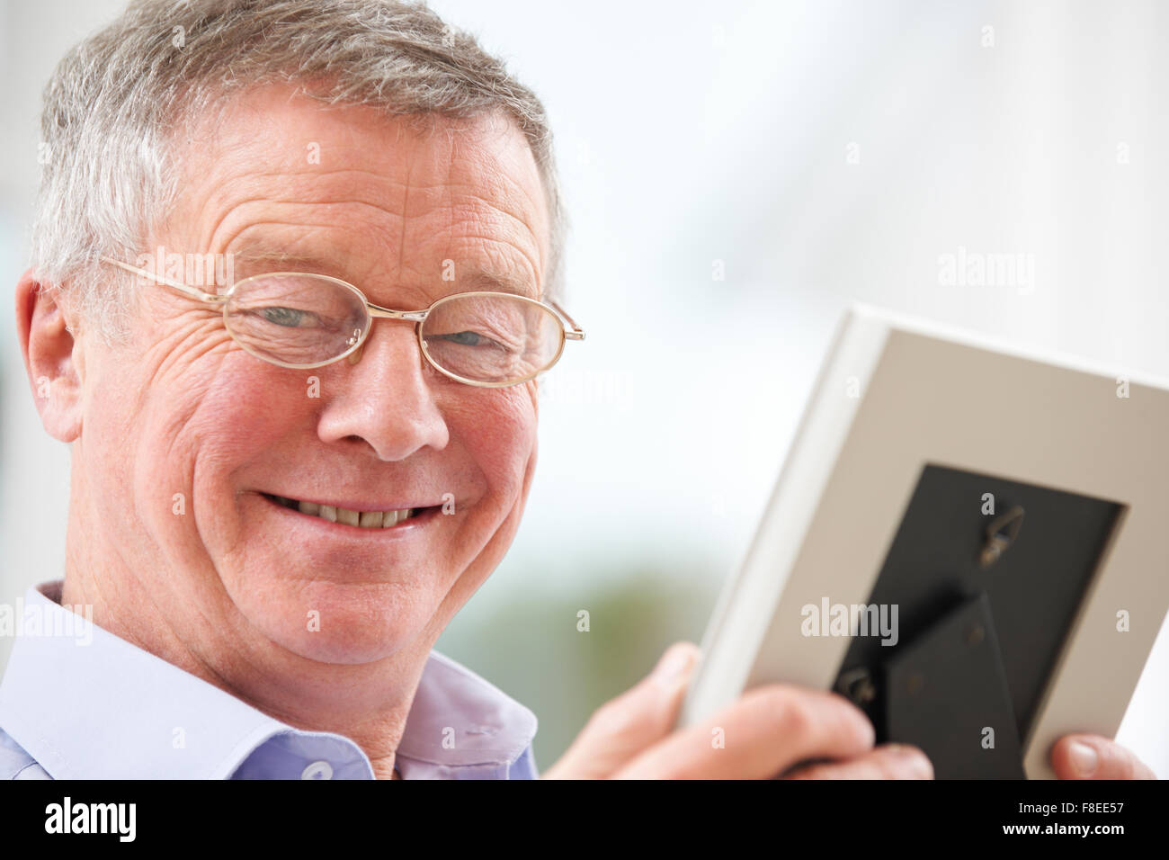 Smiling Senior Man Looking At Photograph In Frame Stock Photo - Alamy