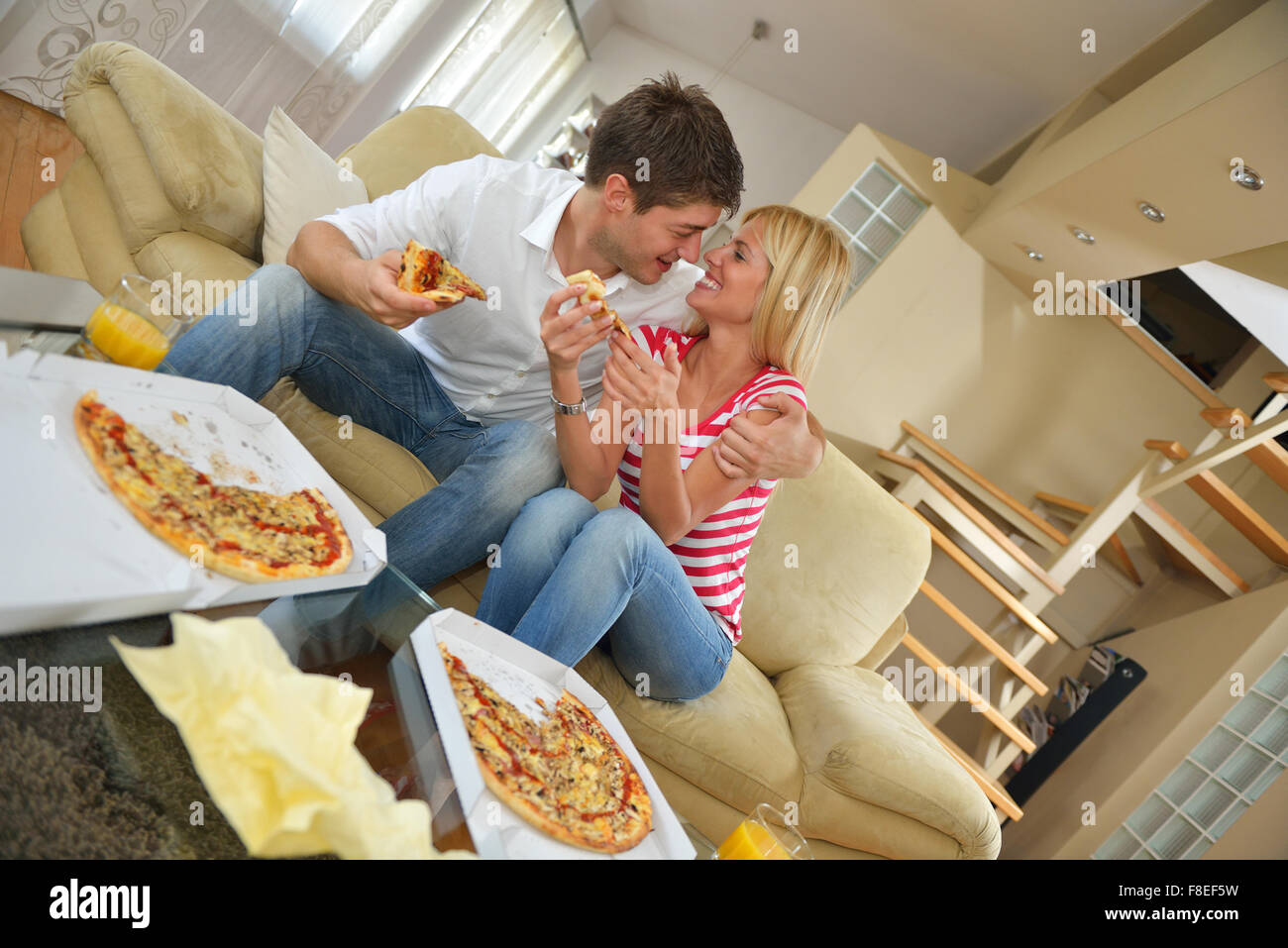 happy young couple eat fresh pizza at home relaxing and watch tv Stock ...