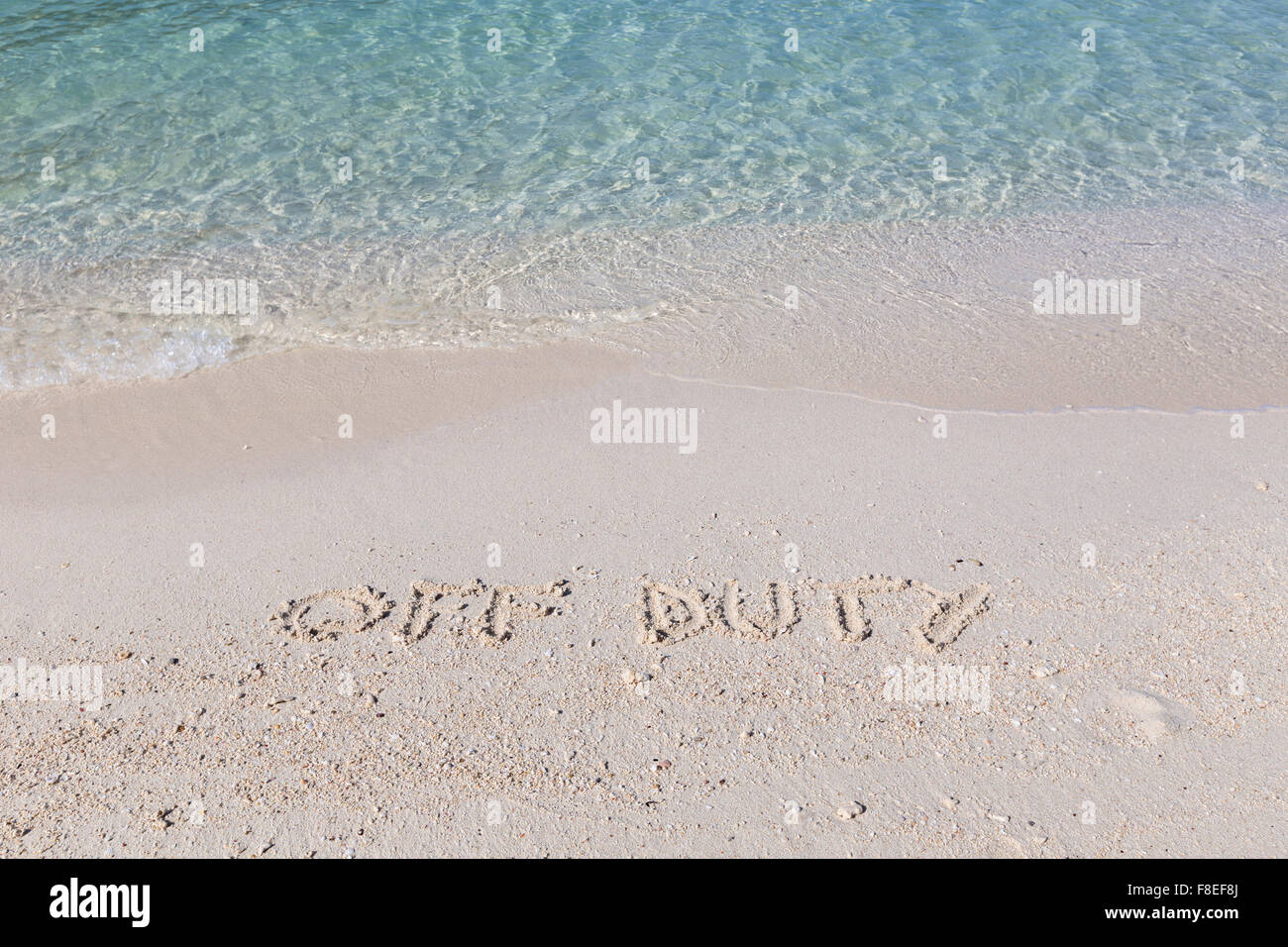 Off duty written out in wet sand on a tropical beach in Thailand Stock ...