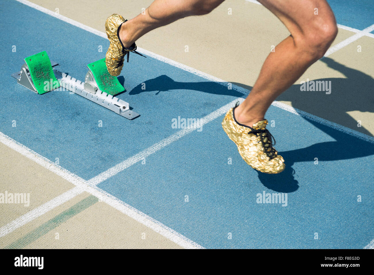 Athlete in gold shoes sprinting from the starting blocks over the ...